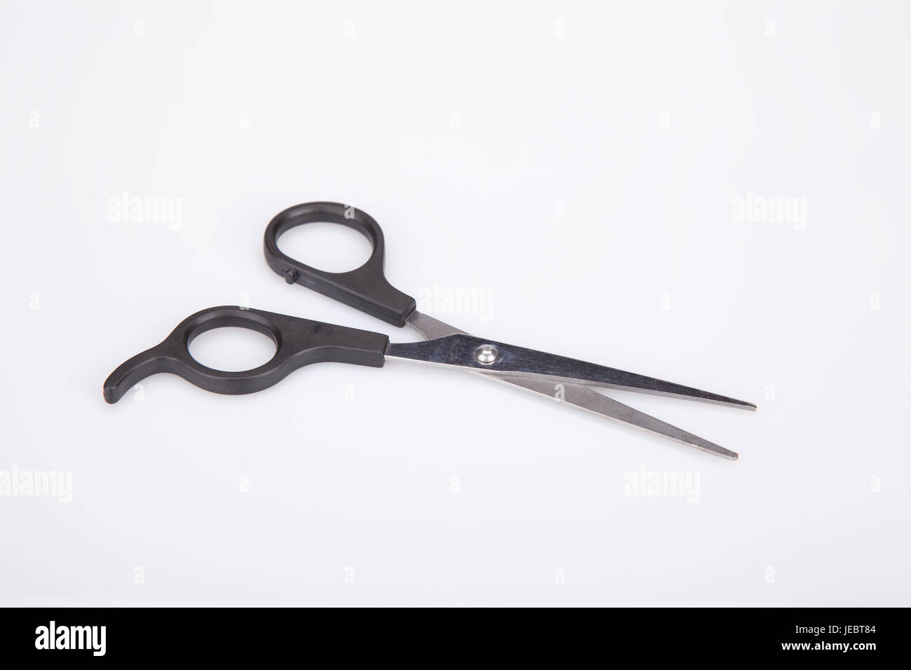 A pair of black scissors on a white surface. Black scissors isolated on ...
