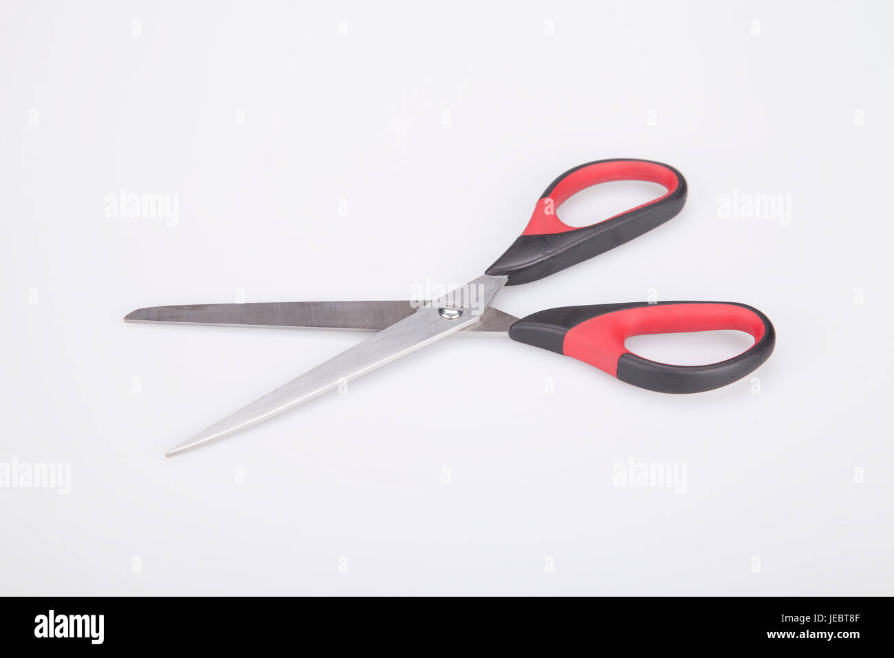 A pair of red scissors on a white surface. Red scissors isolated on ...