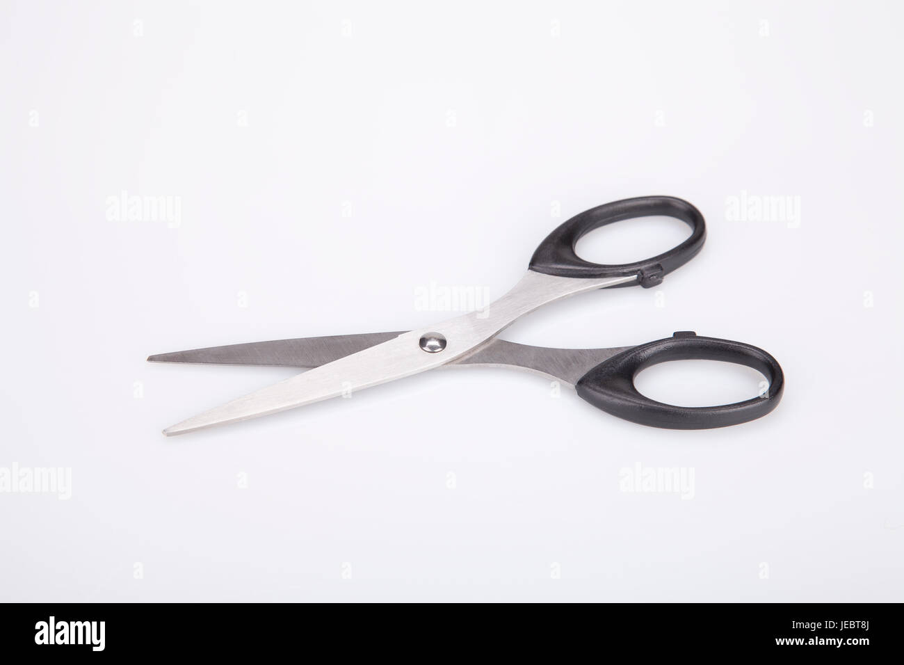 A pair of black scissors on a white surface. Black scissors isolated on ...