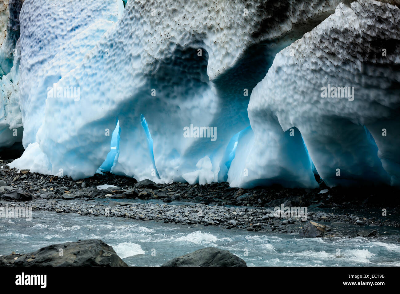 Bright blue ice of glacier overhangs river in beautiful pattern and ...