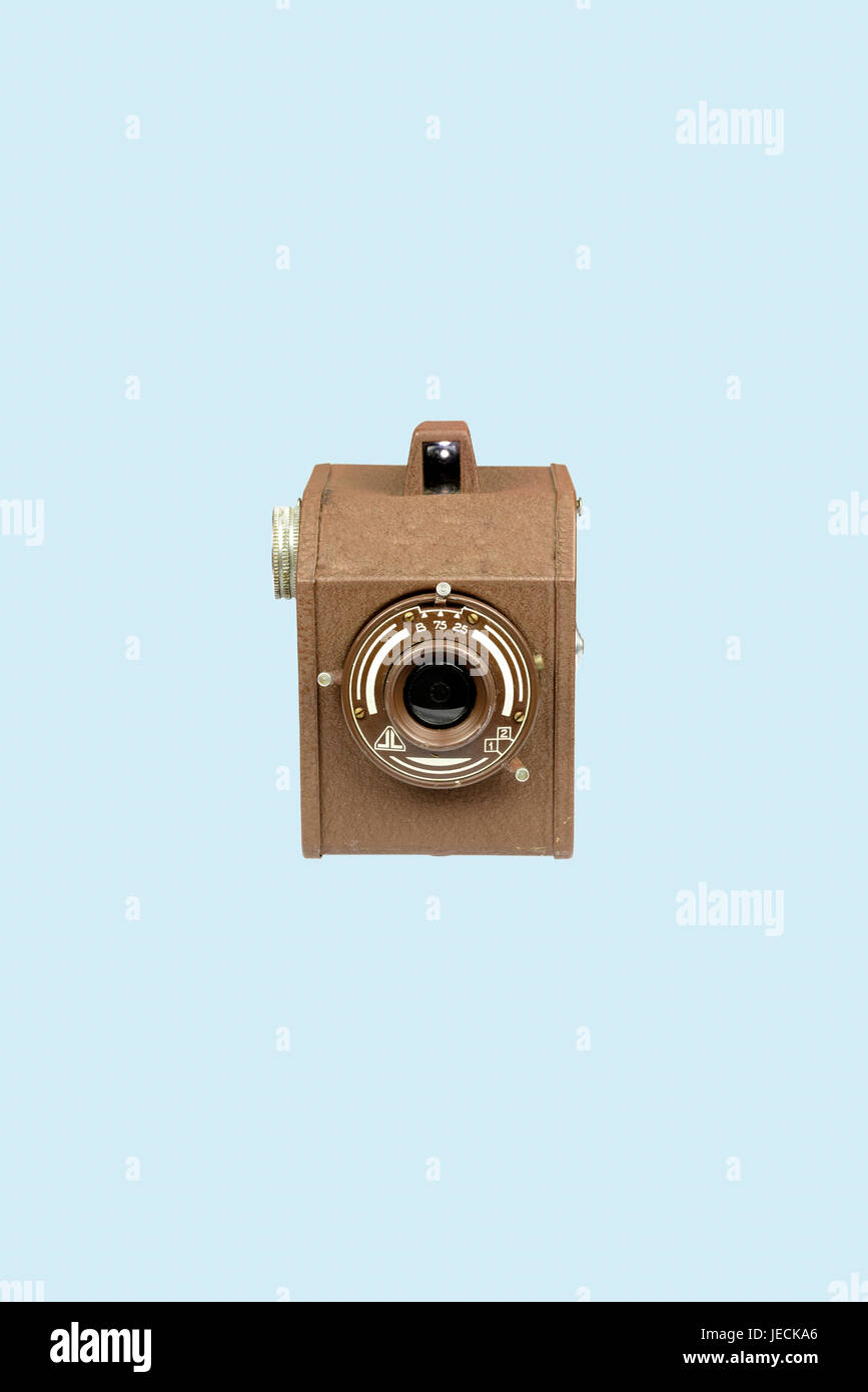 An old-fashioned camera set on a soft light blue background ...