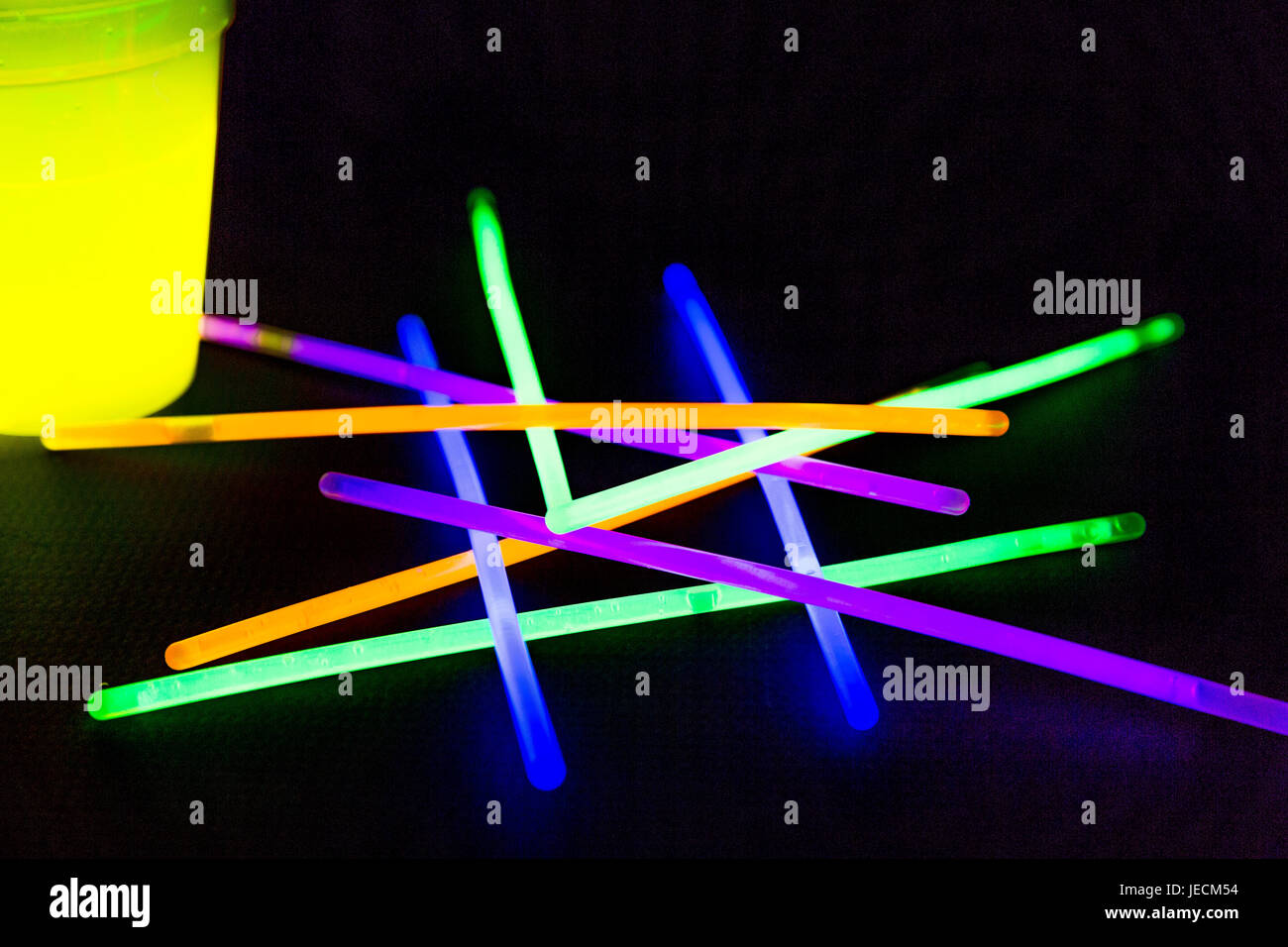 Yellow fluorescent glass with glow sticks neon light on back background ...