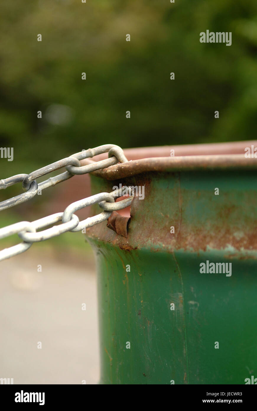Image of a chained rusted garbage can in a park. Selective focus on ...