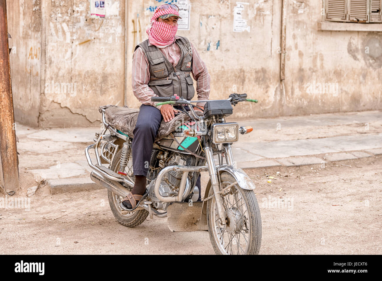 Syrian man wearing a kaffeyah while sitting on his motorcycle on a ...