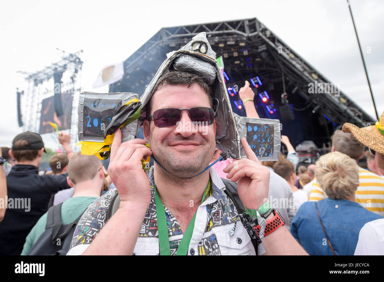 A festivalgoer wears a homemade pyramid stage hat in front of the ...