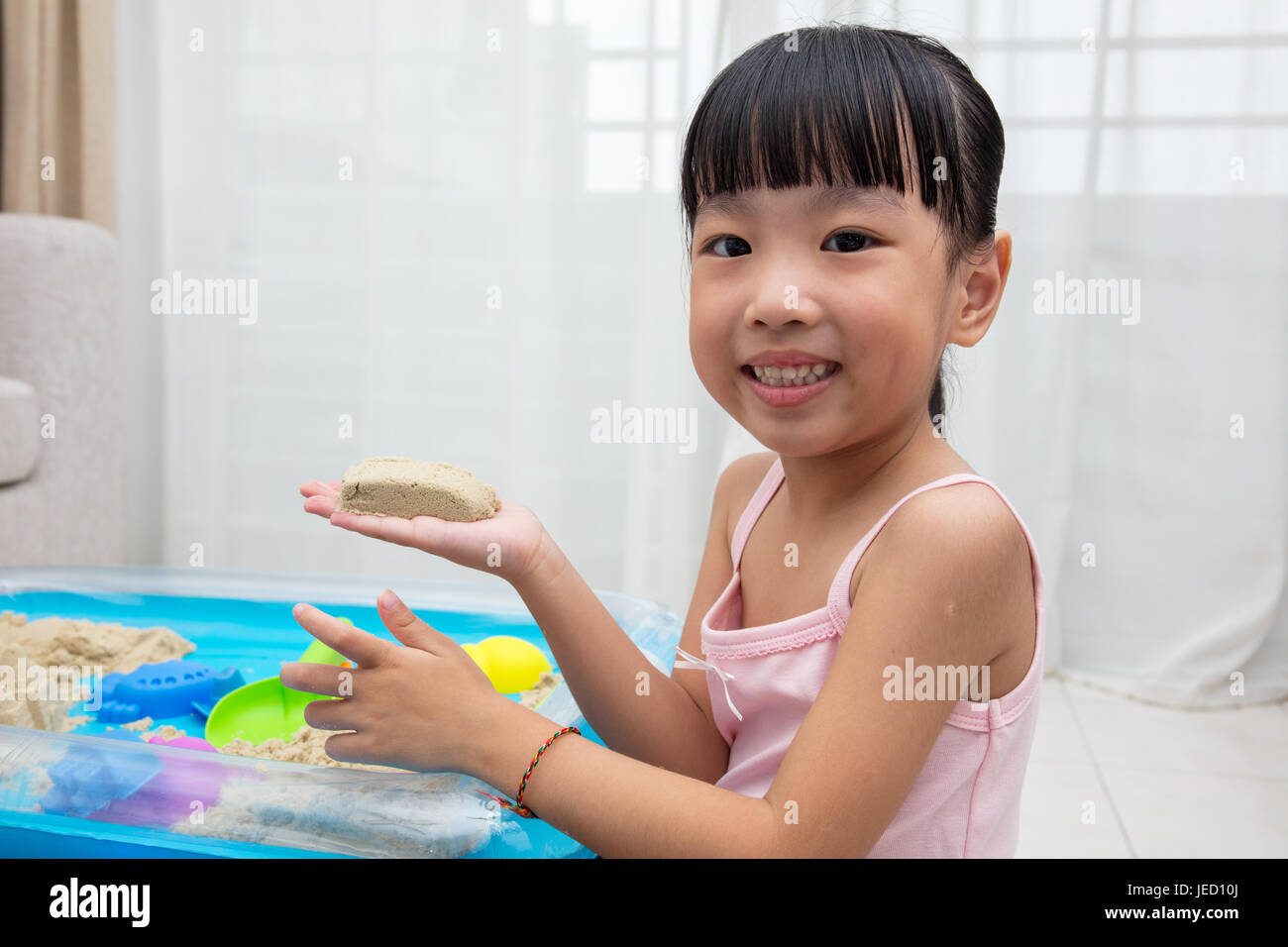 Happy Asian Chinese little girl playing sand in the living room at home ...