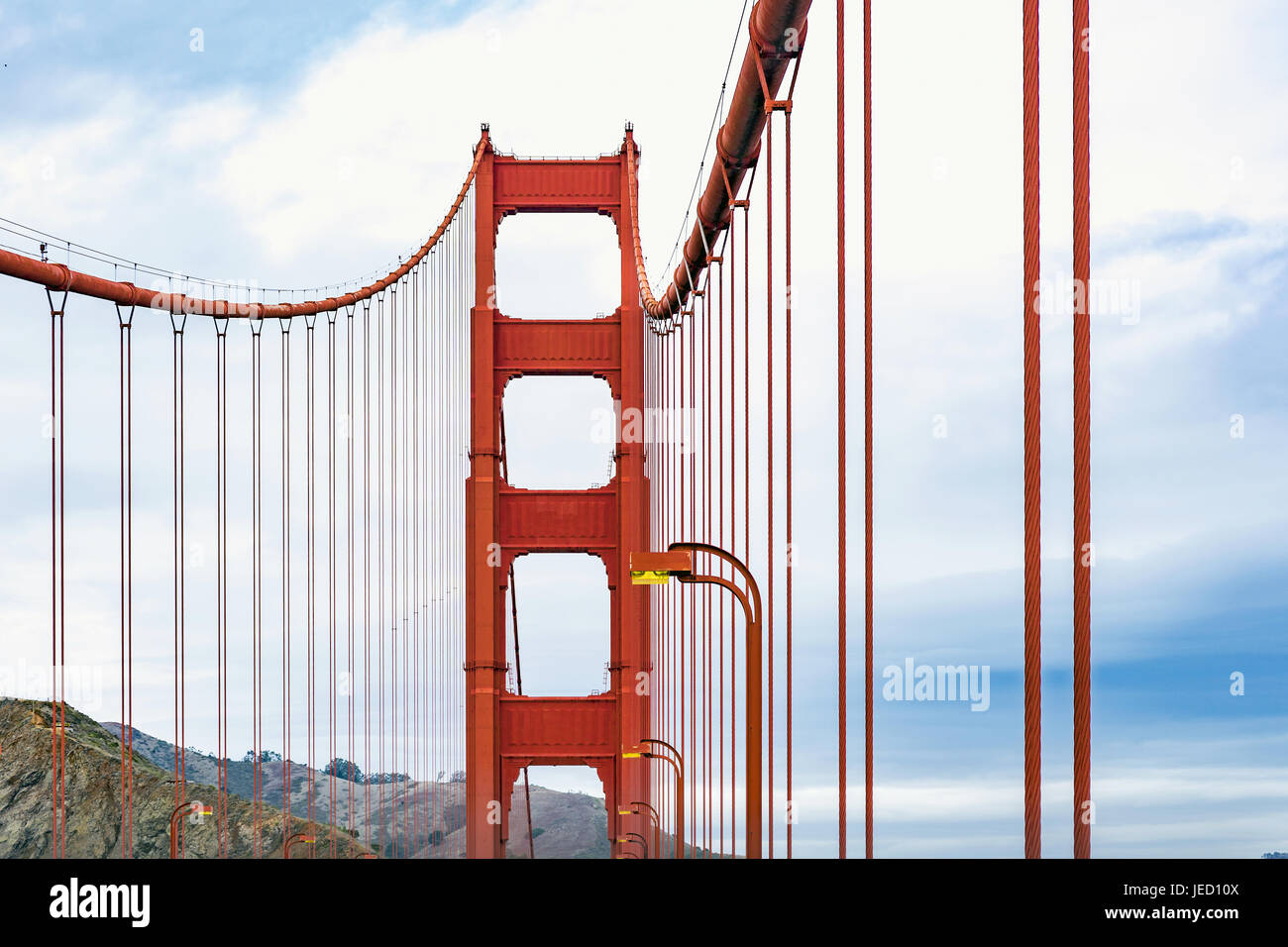 Golden Gate Bridge Tower with street lamps and hills in the distance ...