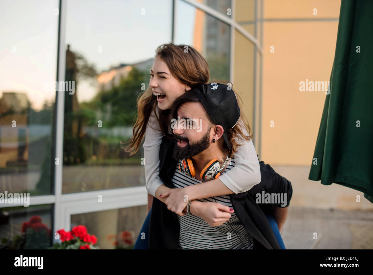 Beautiful couple having fun. Bearded boy riding his girl on his back ...