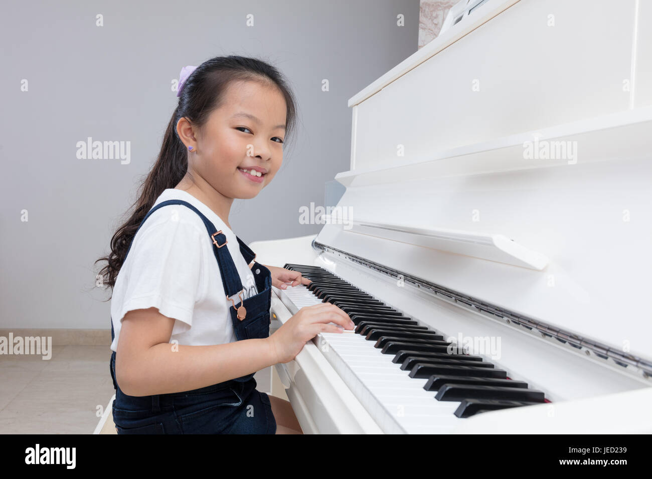 Happy Asian Chinese little girl playing classical piano in the living ...