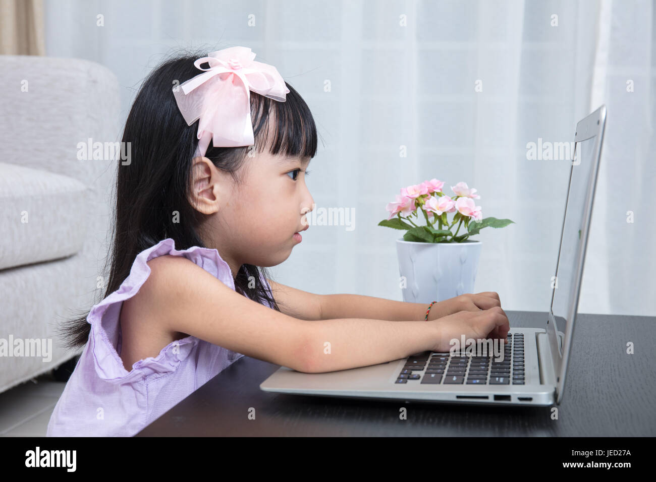 Smiling Asian Chinese little girl using laptop in the living room at ...