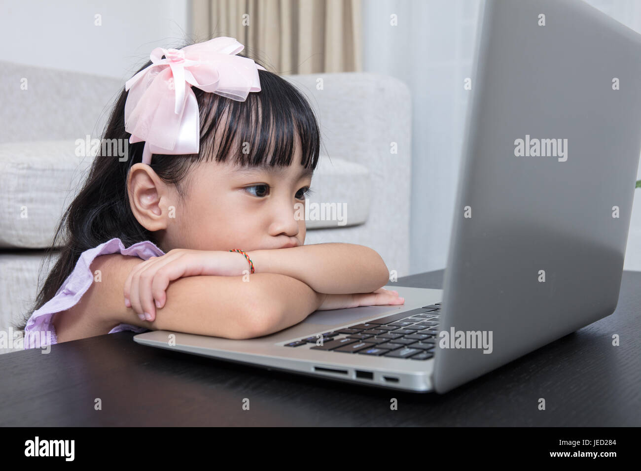 Fatigued Asian Chinese little girl looking at computer screen in the ...
