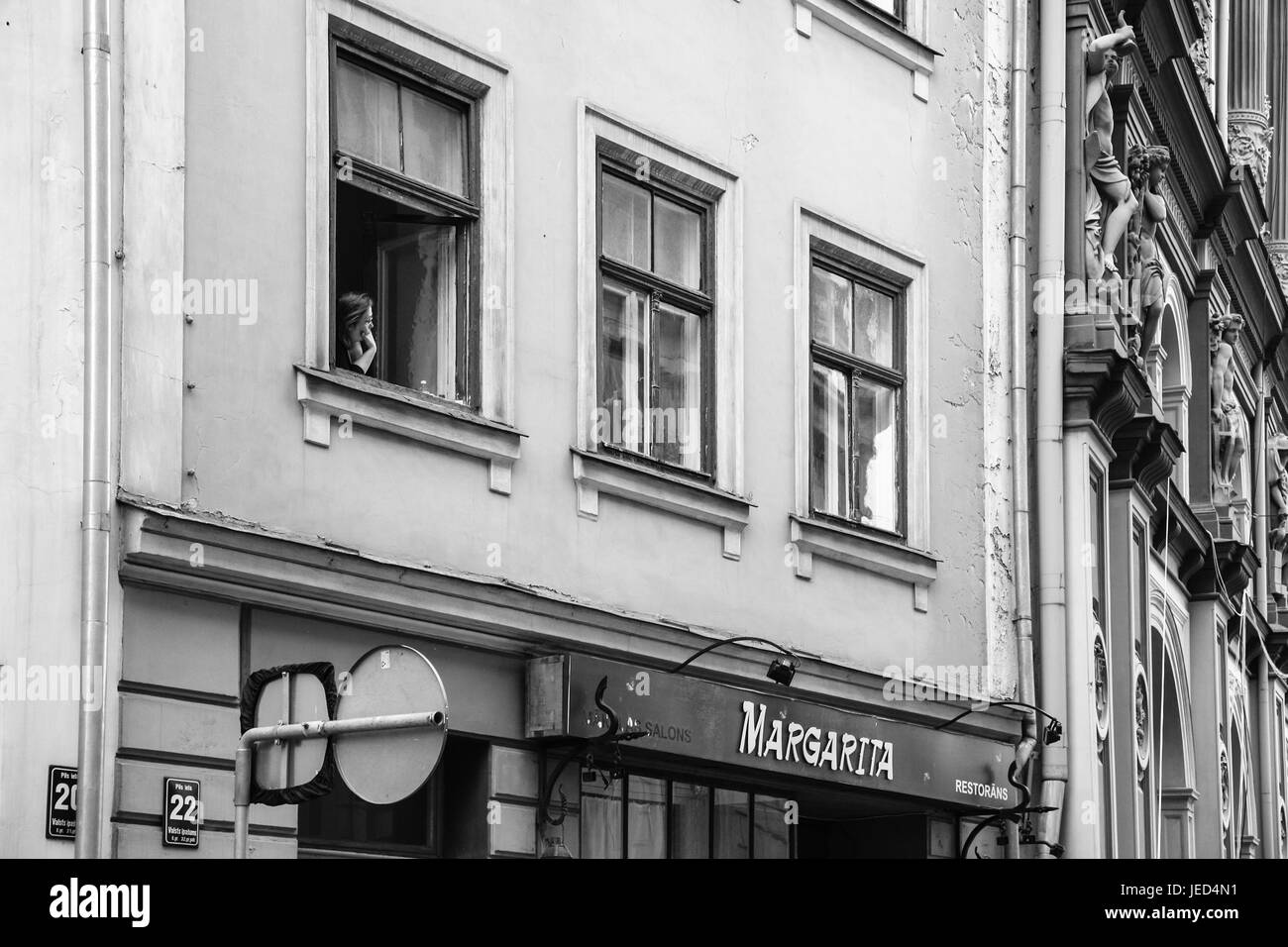RIGA, LATVIA - SEPTEMBER 10, 2008: woman an window of apartment house ...
