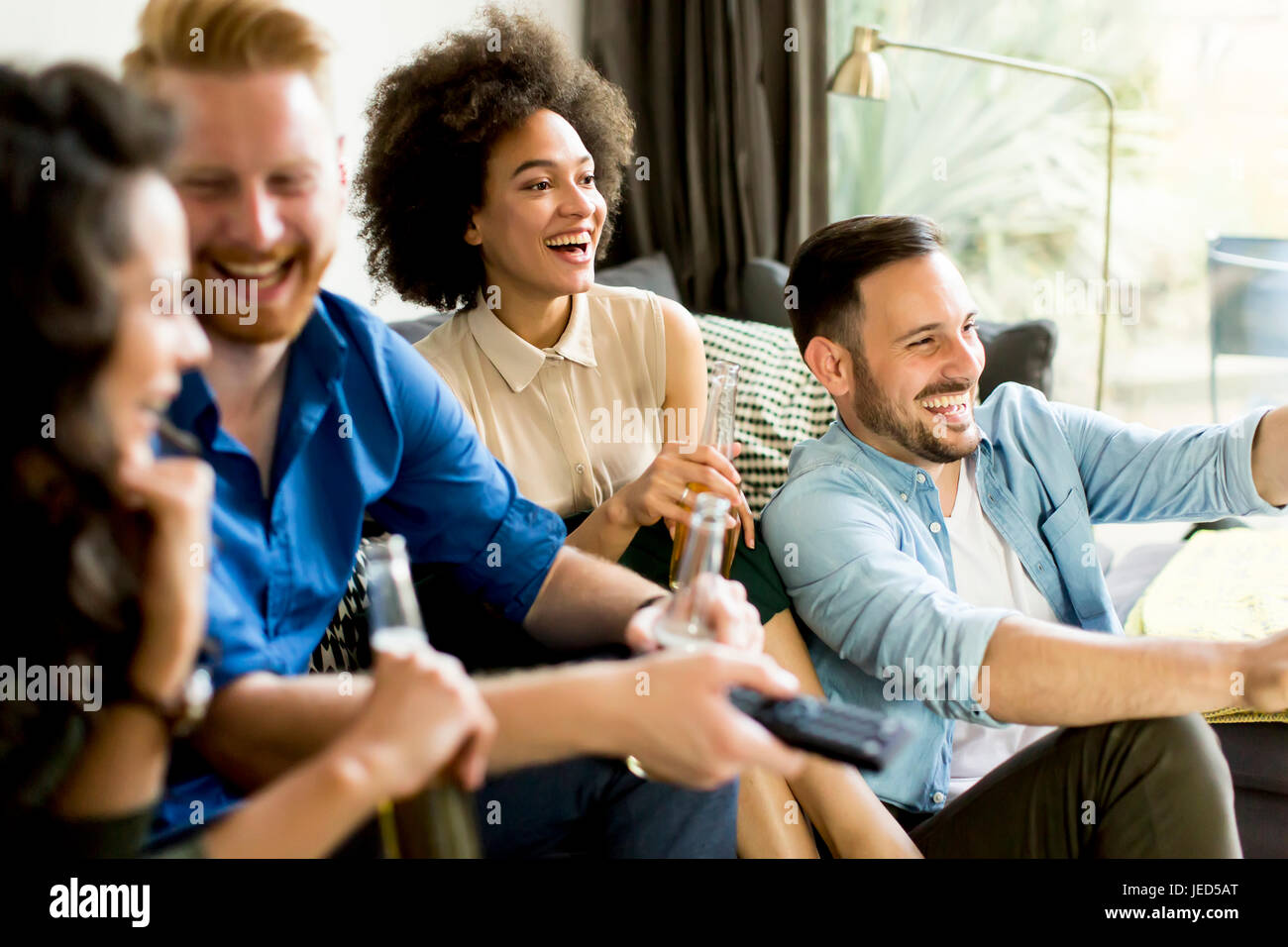 Group of friends watching TV , drinking cider and having fun in the ...