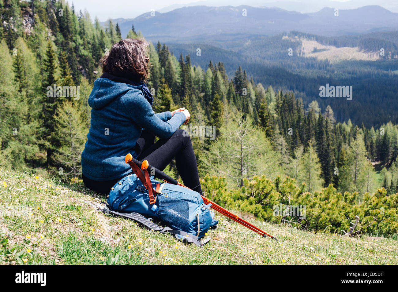 View at female hiker enjoying the mountain air sitting on a grass and ...