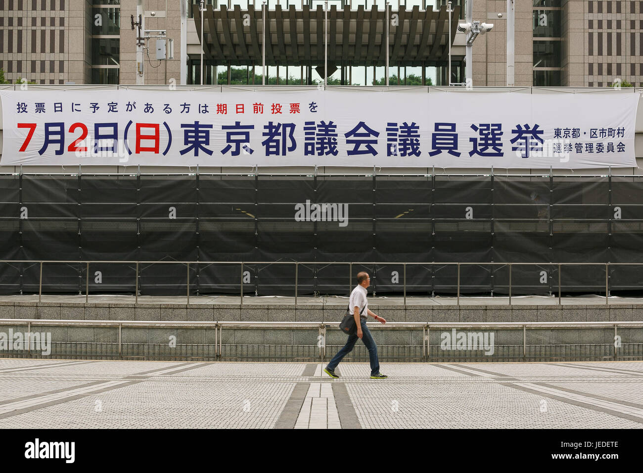 A man walks past a huge banner on display at the Tokyo Metropolitan ...