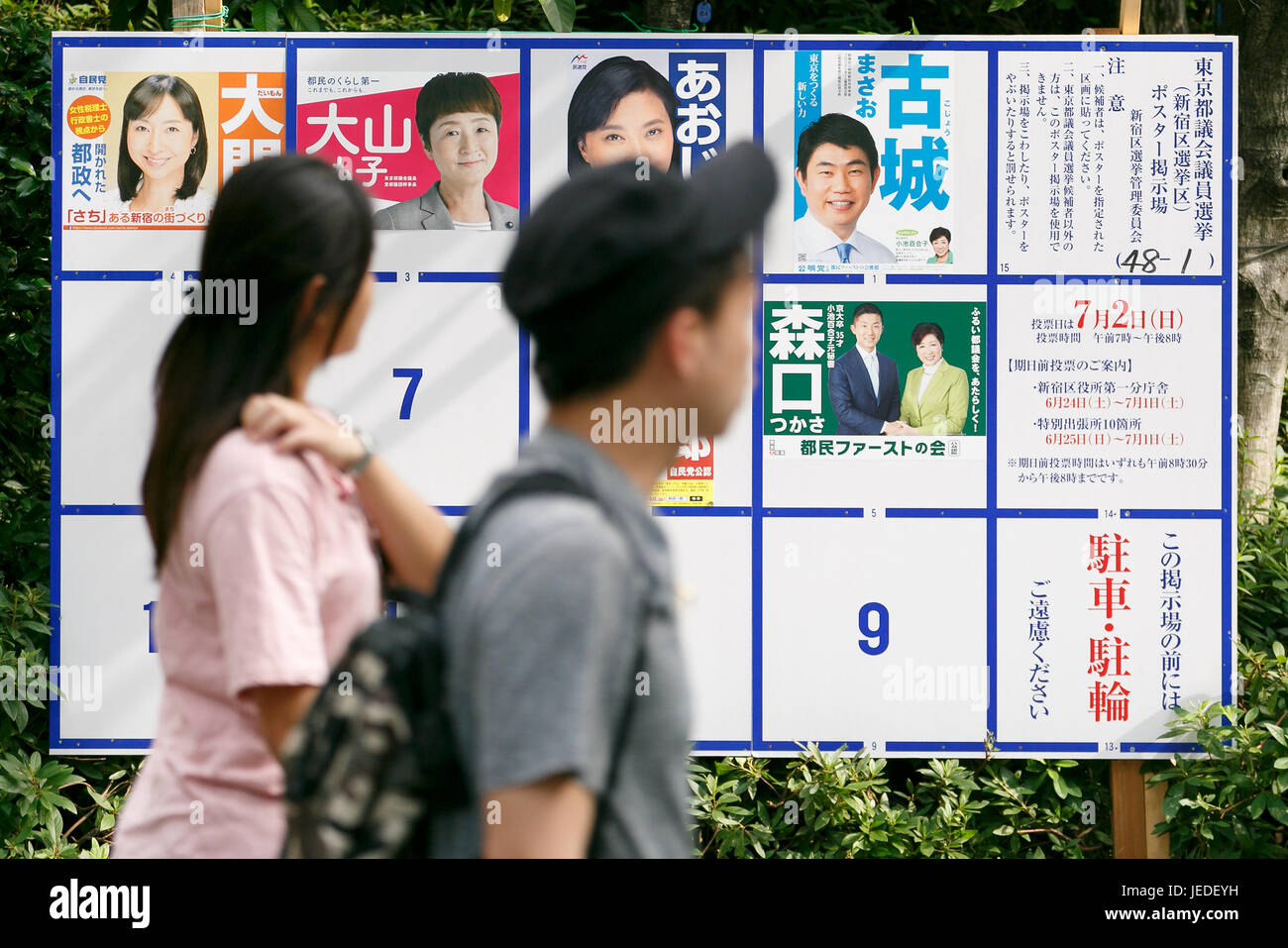 Tokyo, Japan. 24th June, 2017. Pedestrians walk past an election poster ...