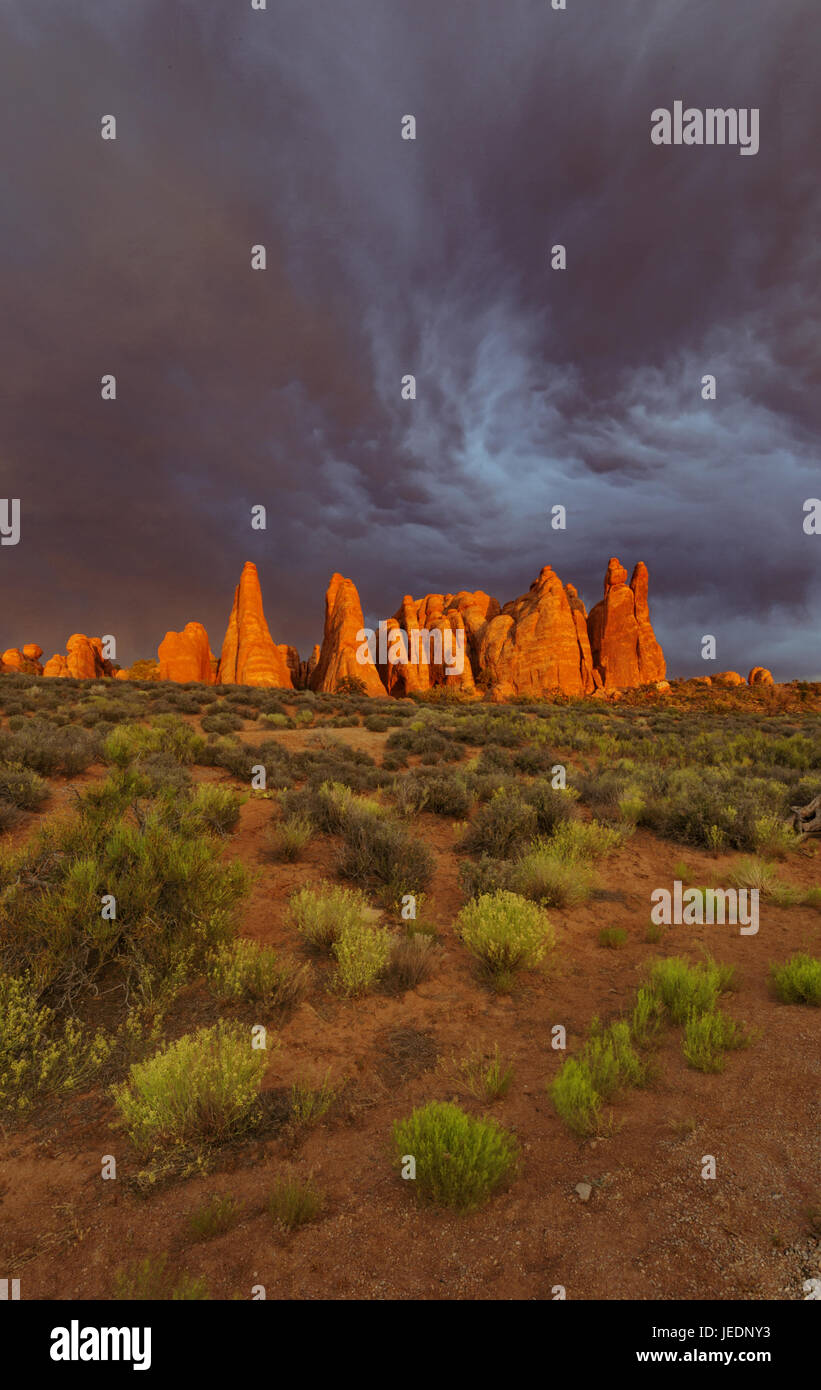 Vertical photograph of sunlit pinnacles with threatening storm clouds ...