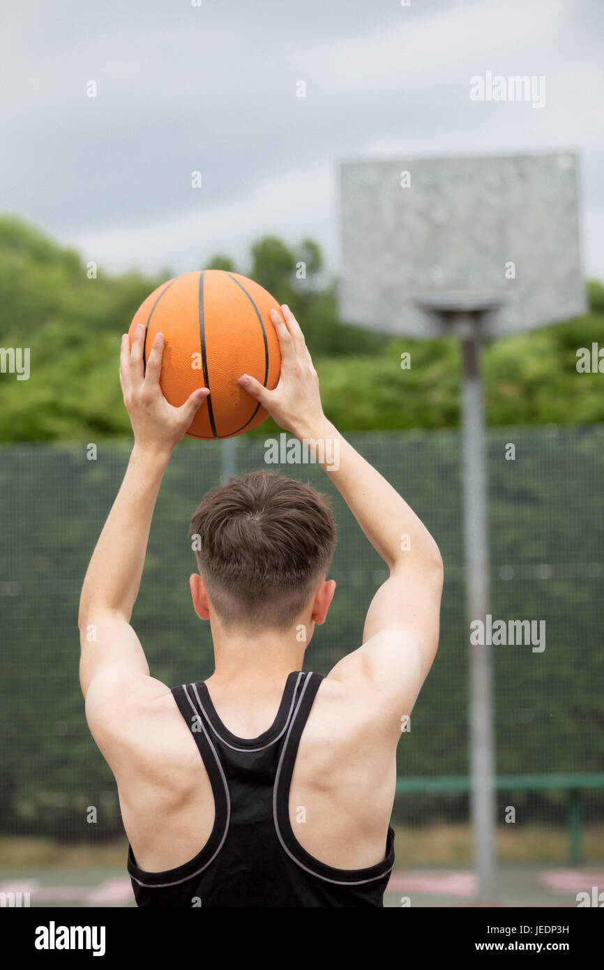 Teenage boy shooting a hoop on a basketball court Stock Photo - Alamy