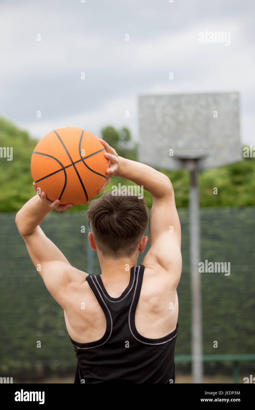 Teenage boy shooting a hoop on a basketball court Stock Photo - Alamy