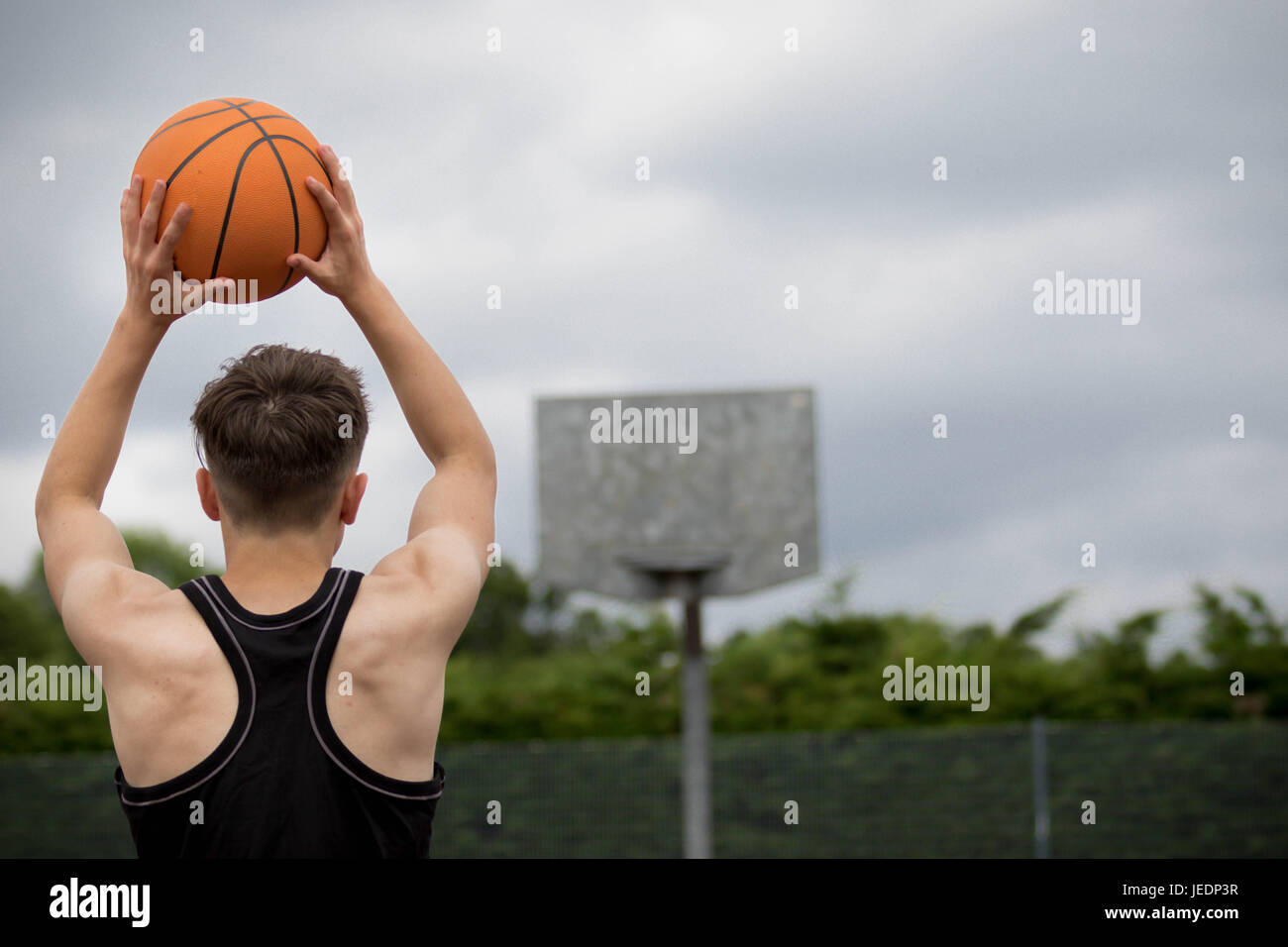Teenage boy shooting a hoop on a basketball court Stock Photo - Alamy