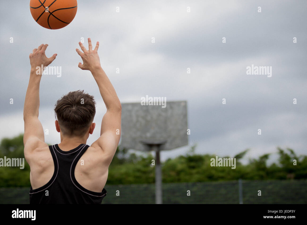 Teenage boy shooting a hoop on a basketball court Stock Photo - Alamy