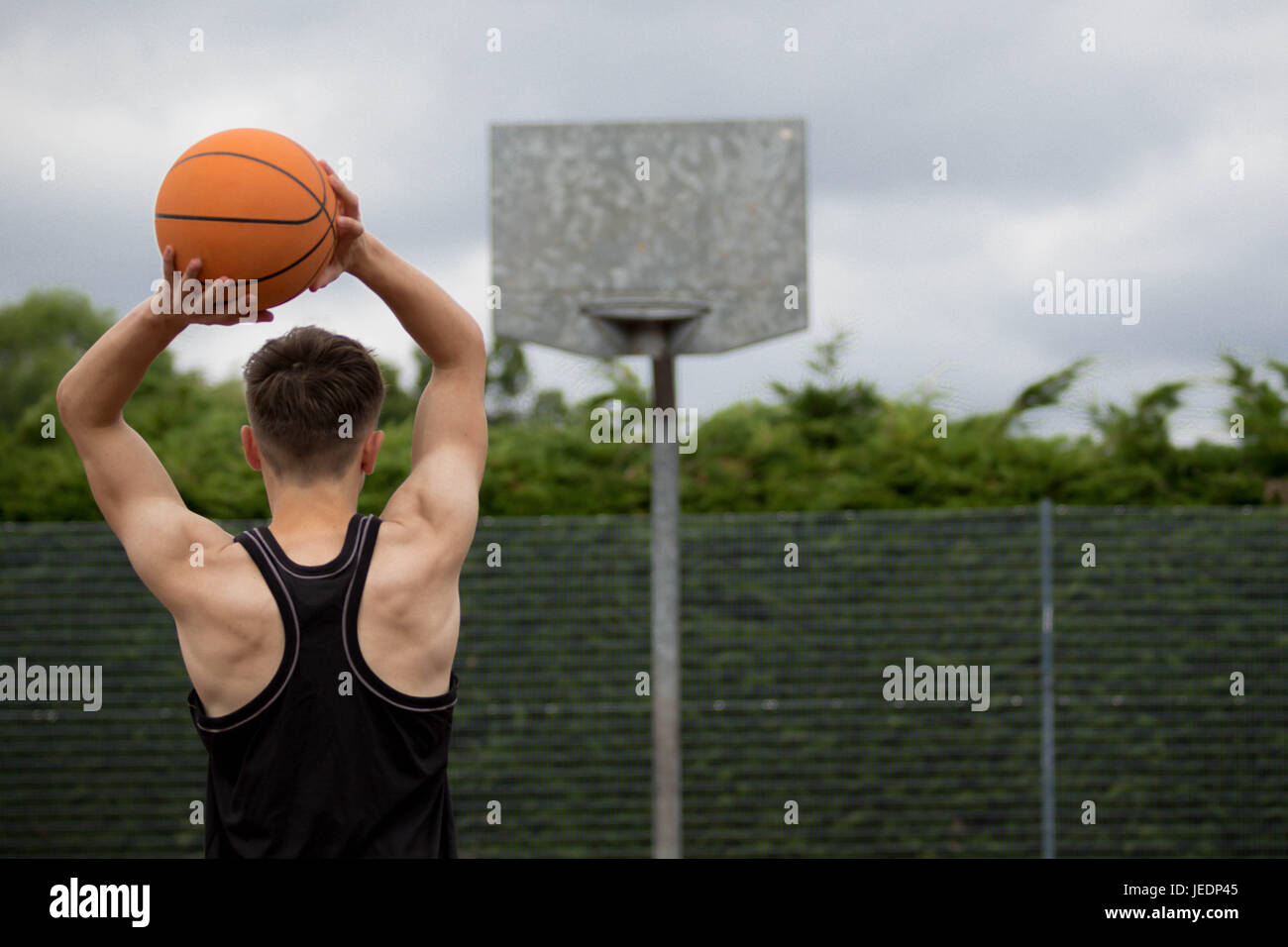 Teenage boy shooting a hoop on a basketball court Stock Photo - Alamy