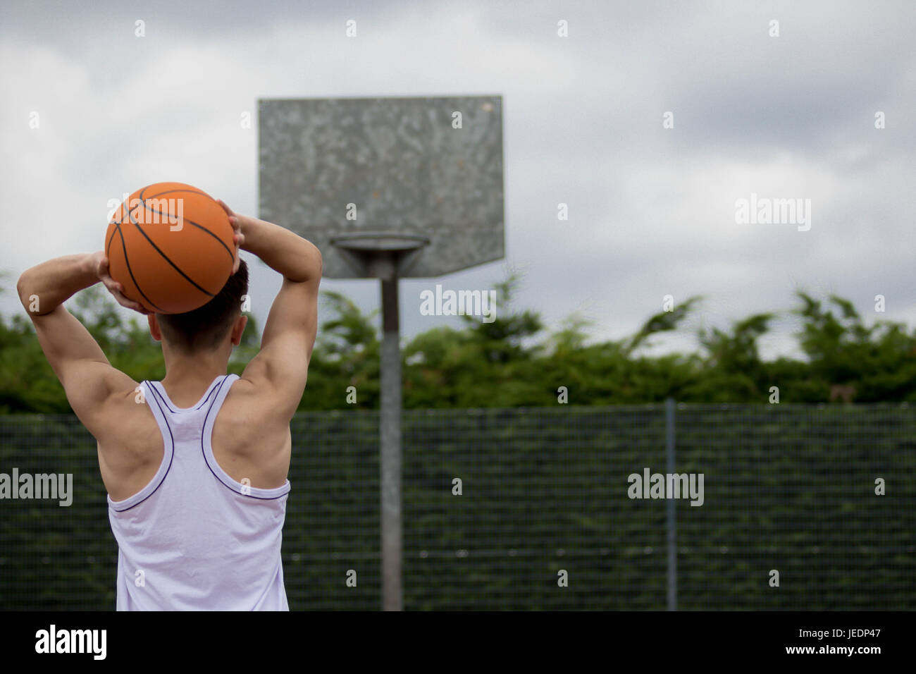 Teenage boy shooting a hoop on a basketball court Stock Photo - Alamy