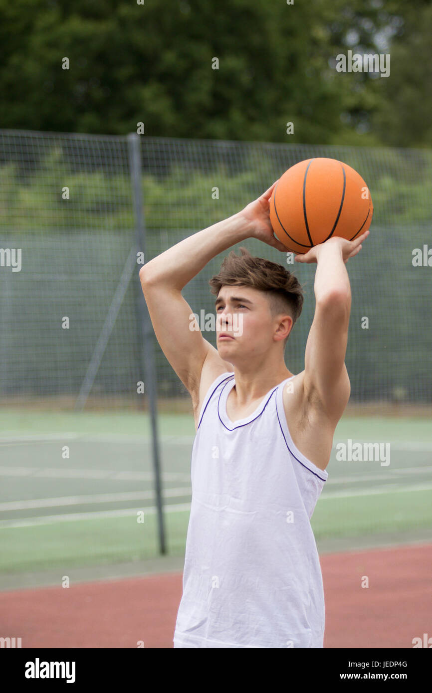 Teenage boy shooting a hoop on a basketball court Stock Photo - Alamy