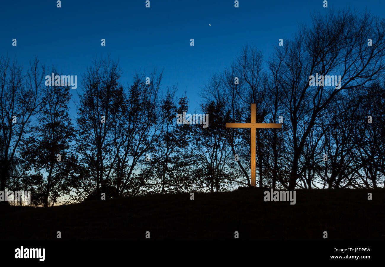 Warm colored cross at dawn with autumn trees behind it Stock Photo - Alamy