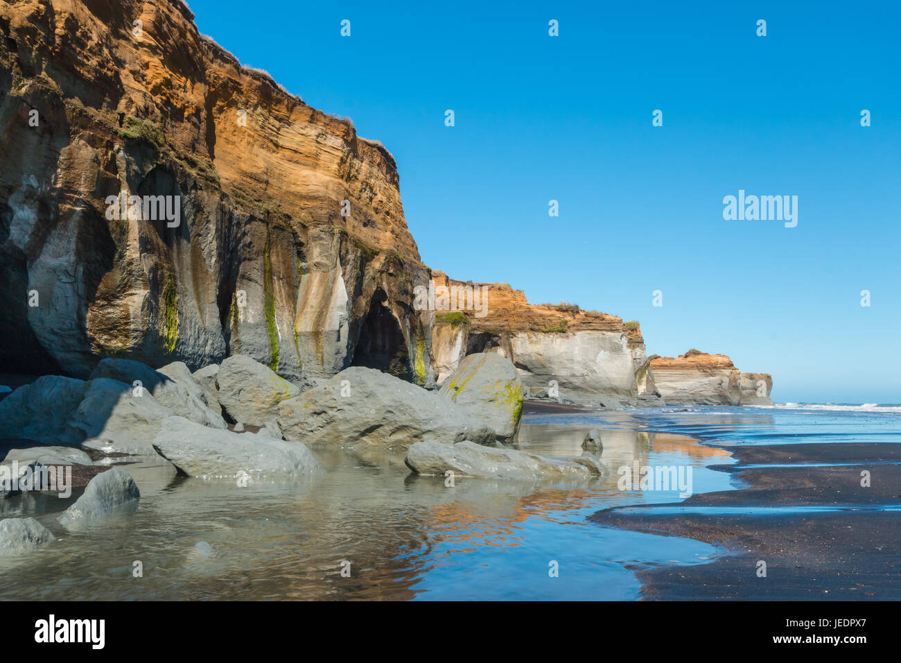 Cliffs of Waverley Beach as the tide goes out leaving pools of water ...