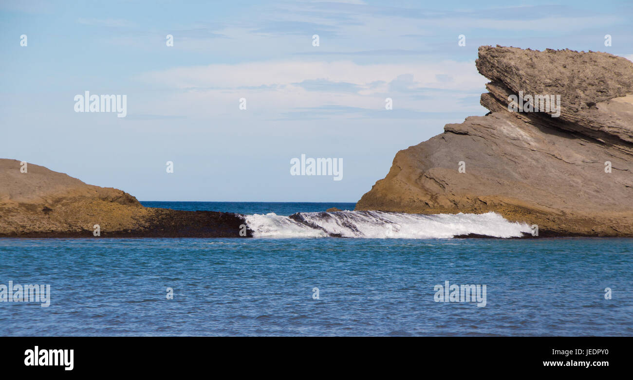 Waves wash over a low part of a rock wall reef Stock Photo - Alamy