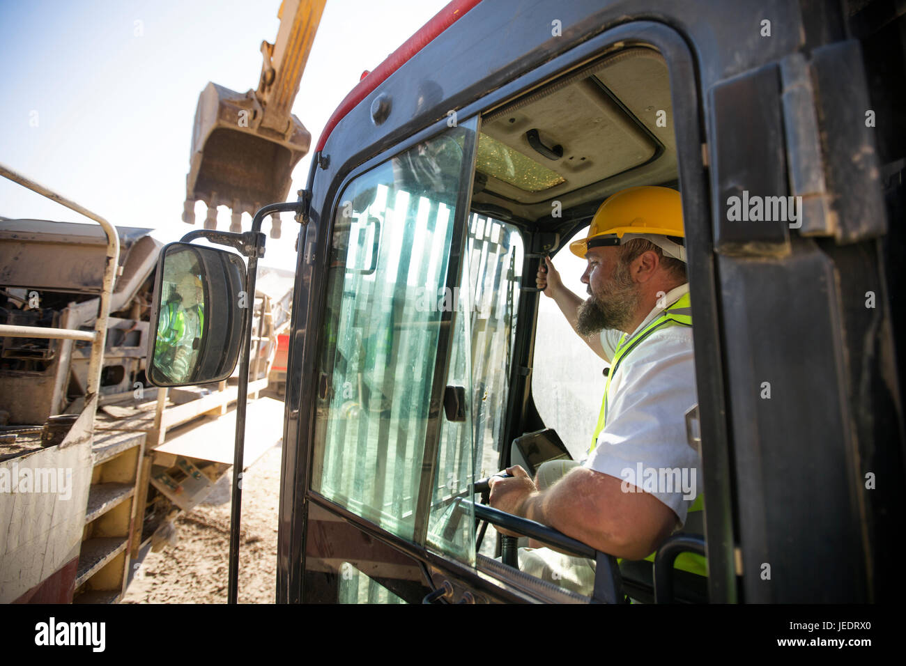 Worker driving a digger Stock Photo - Alamy