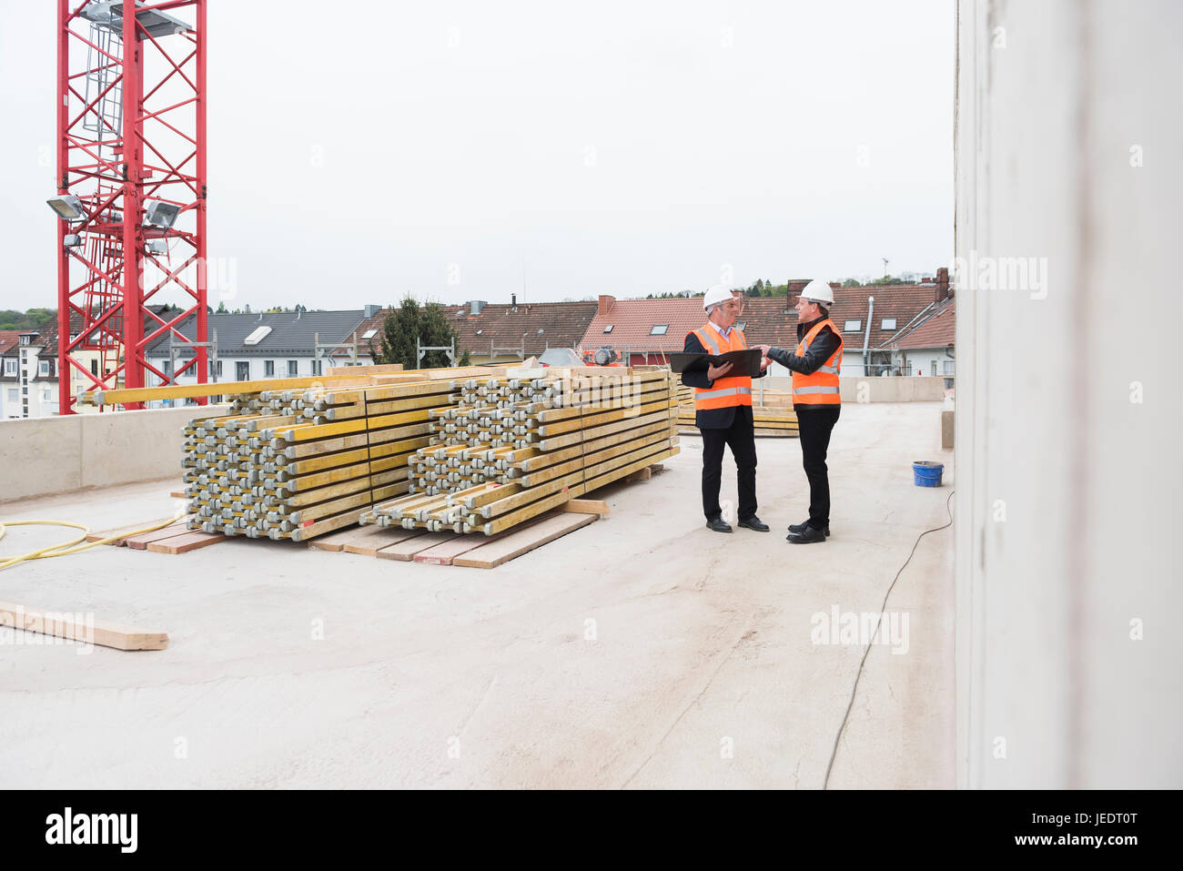 Two men wearing safety vests talking on construction site Stock Photo ...