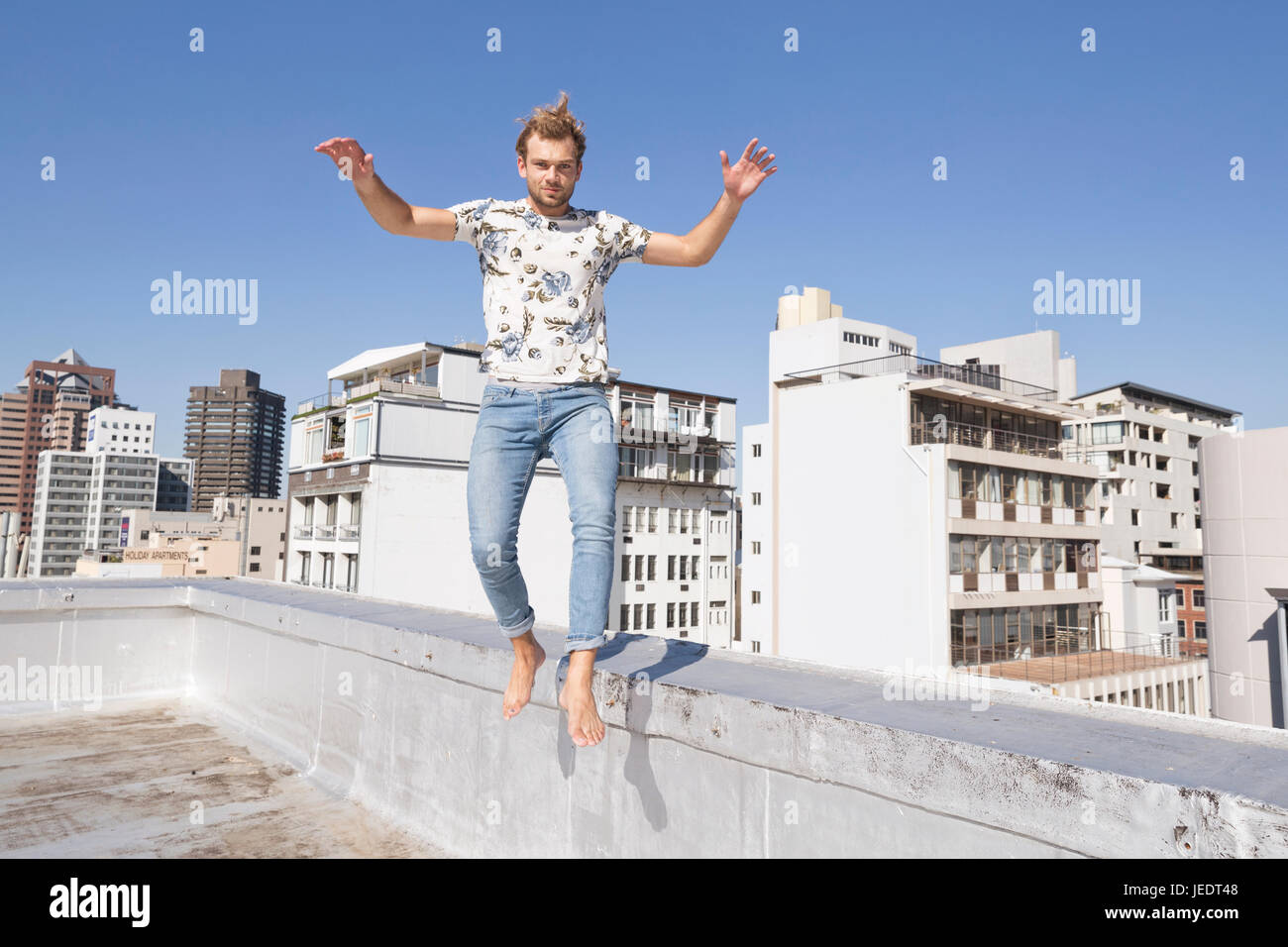 Barefooted man jumping from balustrade of a rooftop terrace Stock Photo ...