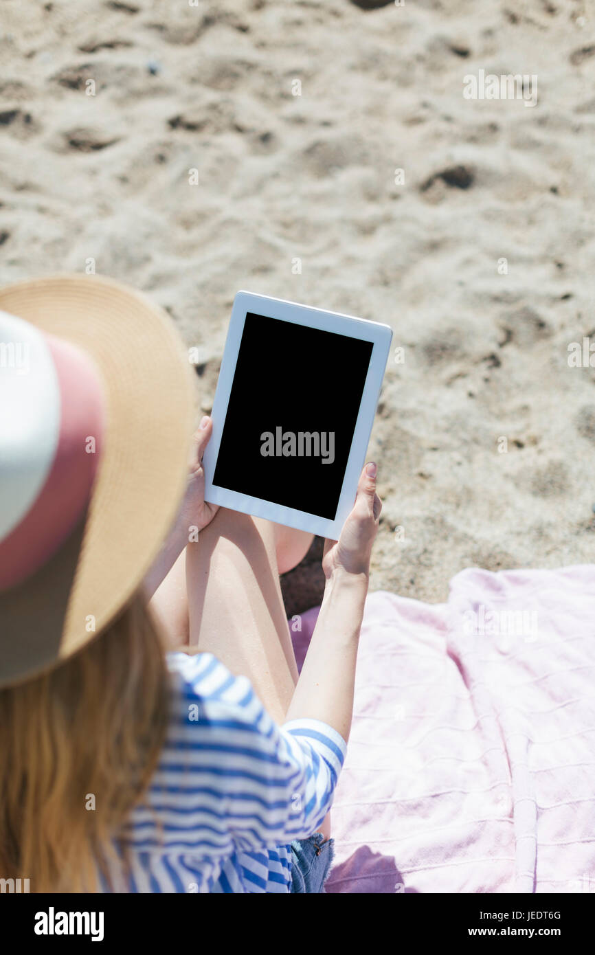 Woman sitting on the beach with tablet Stock Photo - Alamy