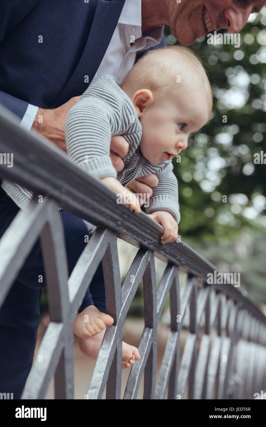 Father holding his baby to look over a fence Stock Photo - Alamy
