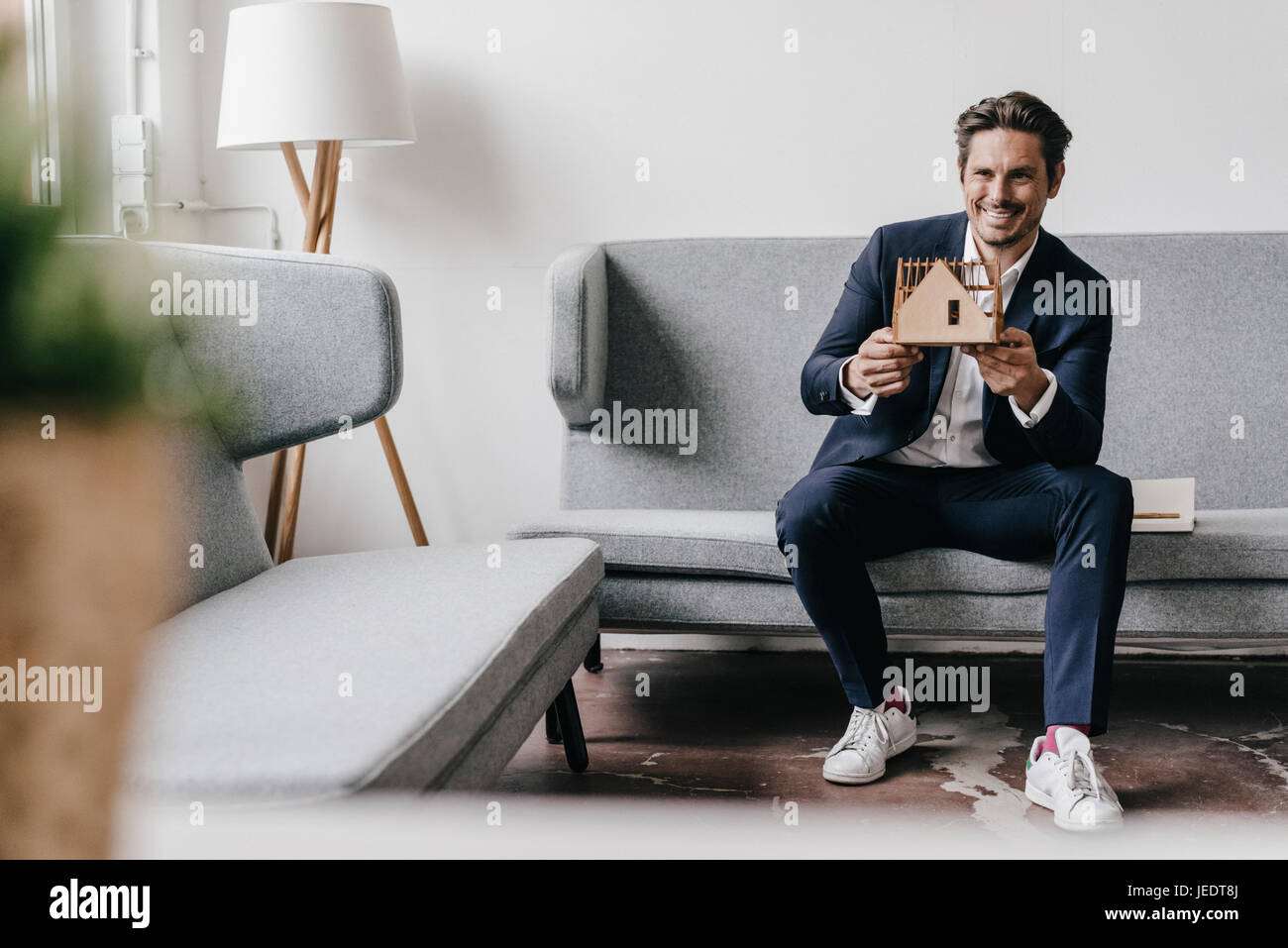 Smiling architect on couch holding architectural model Stock Photo - Alamy