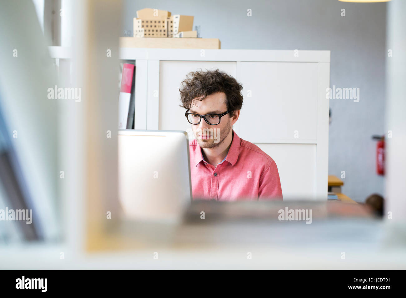 Man in office looking at computer screen Stock Photo - Alamy
