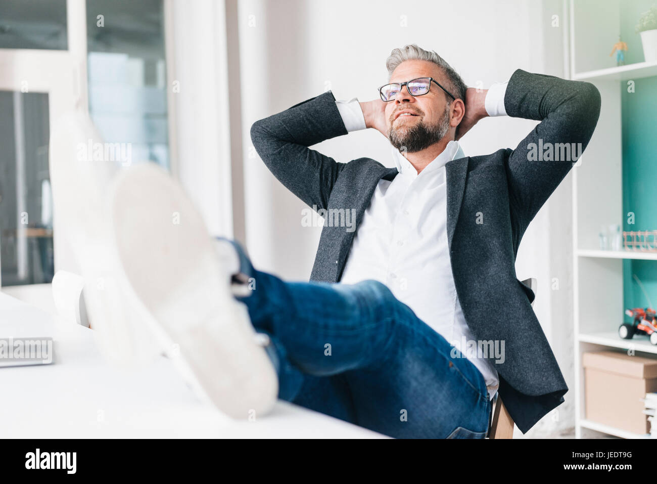 Businessman sitting in office with feet on desk Stock Photo - Alamy