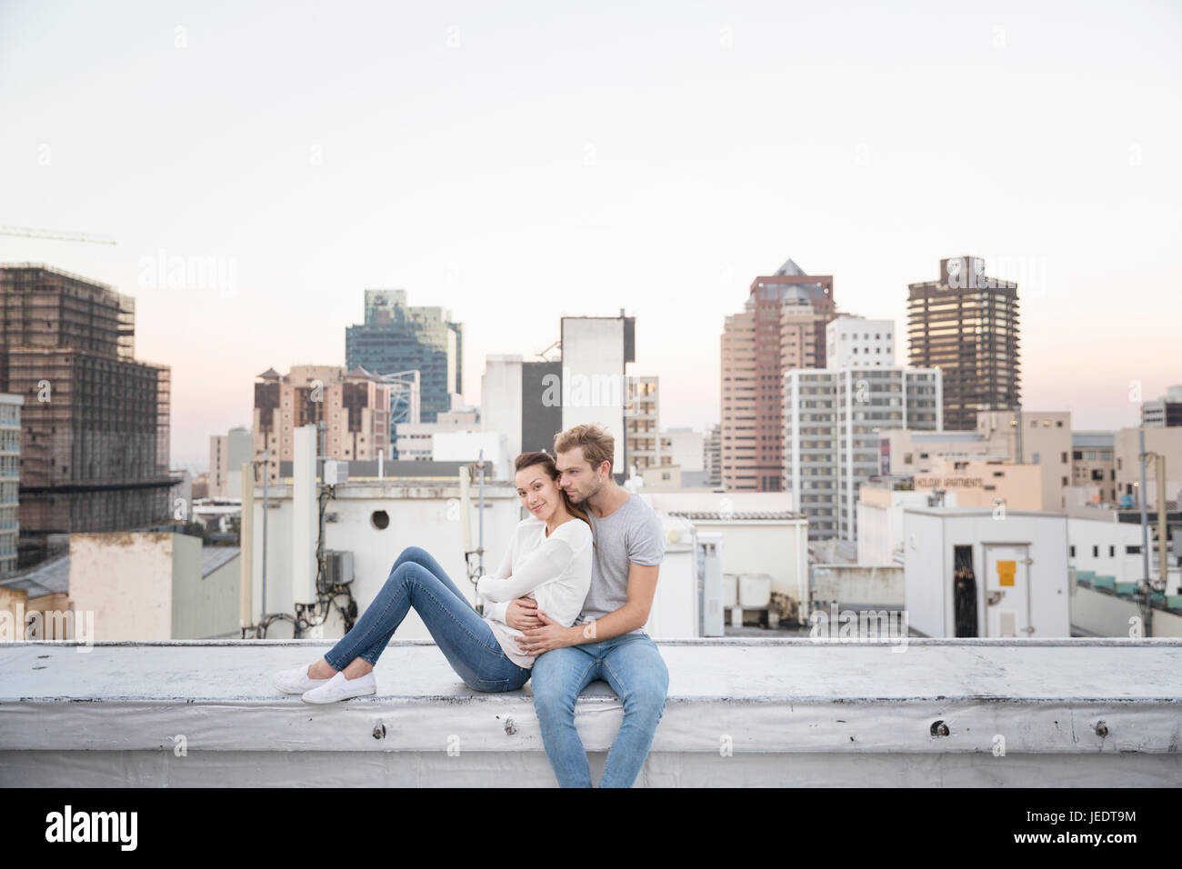 Romantic couple sitting on rooftop terrace, enjoying the view Stock ...