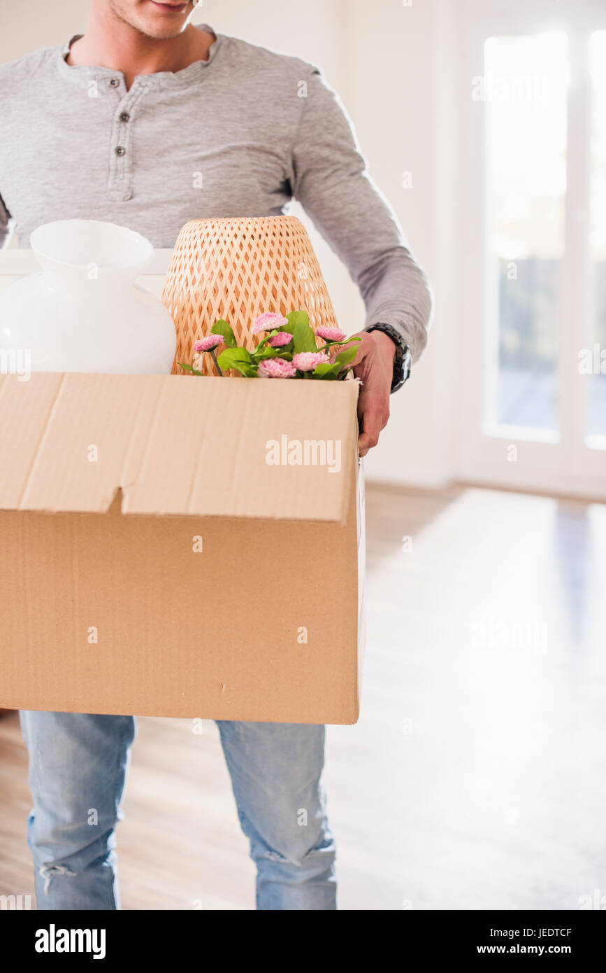 Young man carrying cardboard box in new home Stock Photo - Alamy
