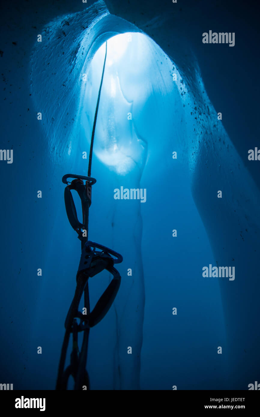 Two ascenders on a rope leading up and out of a large moulin inside of ...