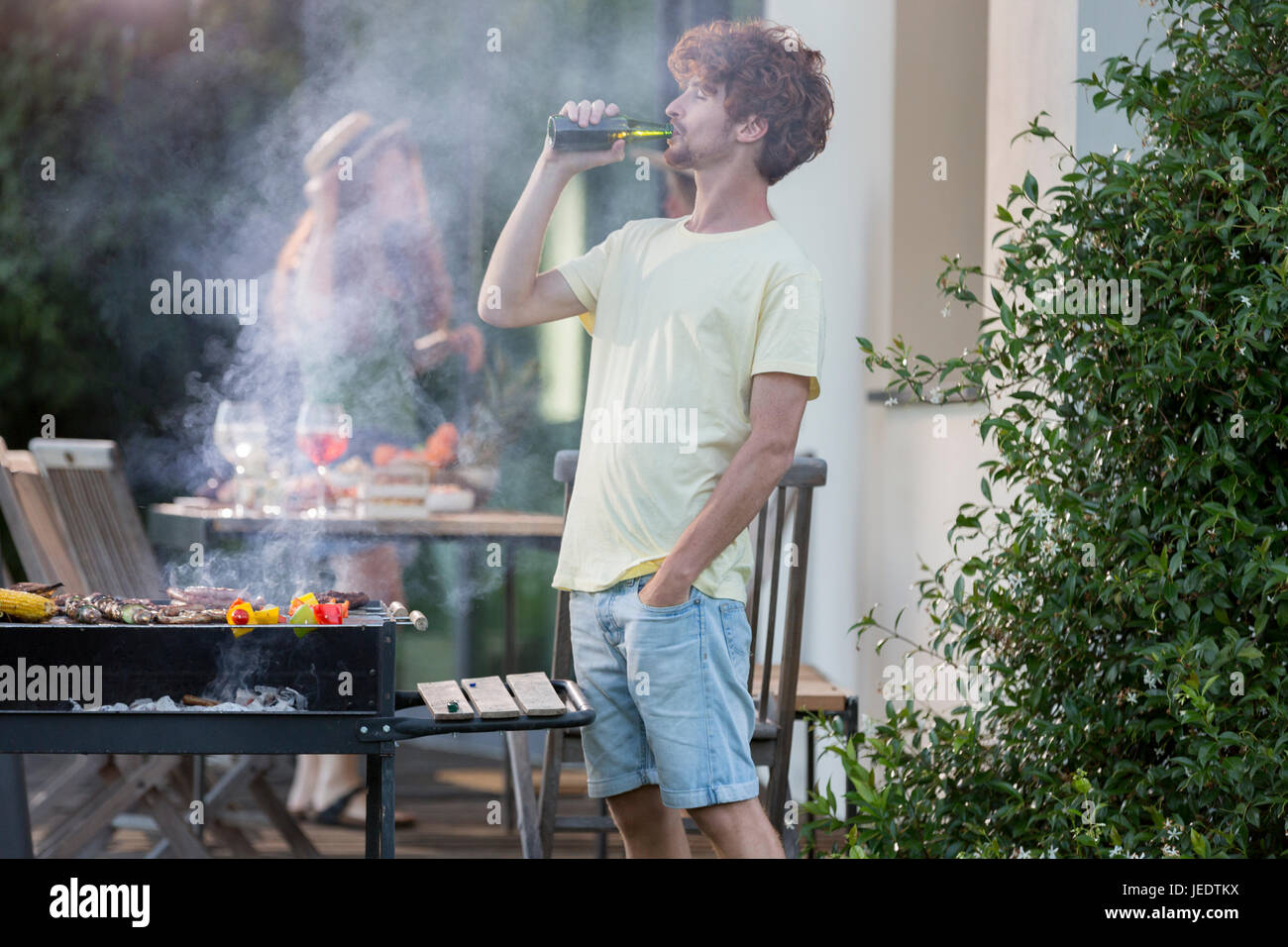 Man having a beer at barbecue grill Stock Photo - Alamy