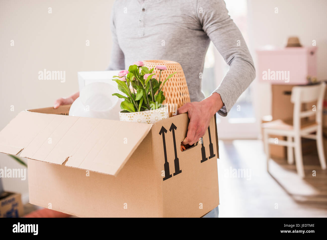 Young man carrying cardboard box in new home Stock Photo - Alamy