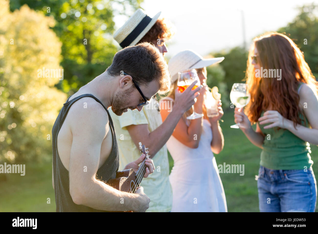 Four friends having fun in the garden at sunset Stock Photo - Alamy