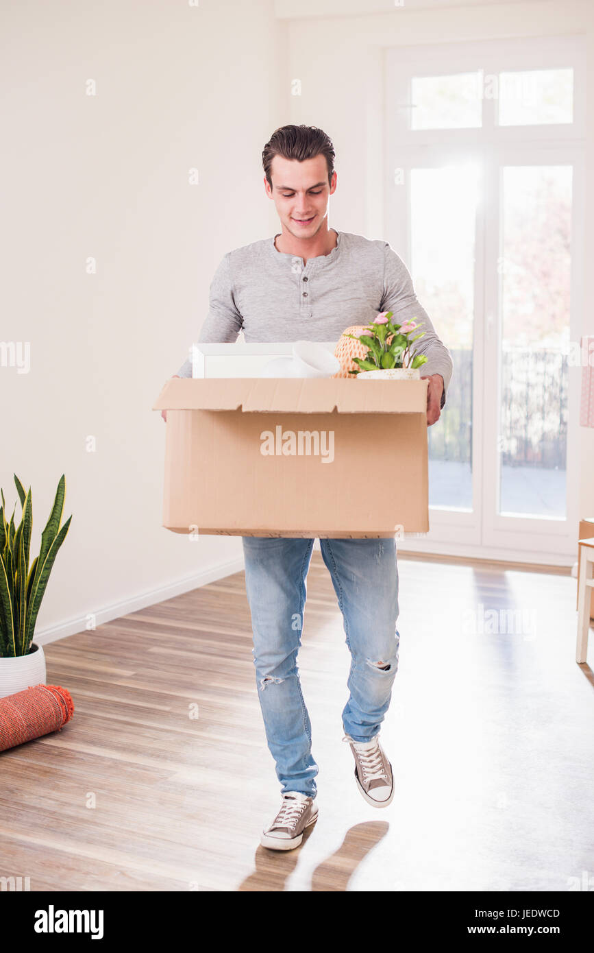 Young man carrying cardboard box in new home Stock Photo - Alamy