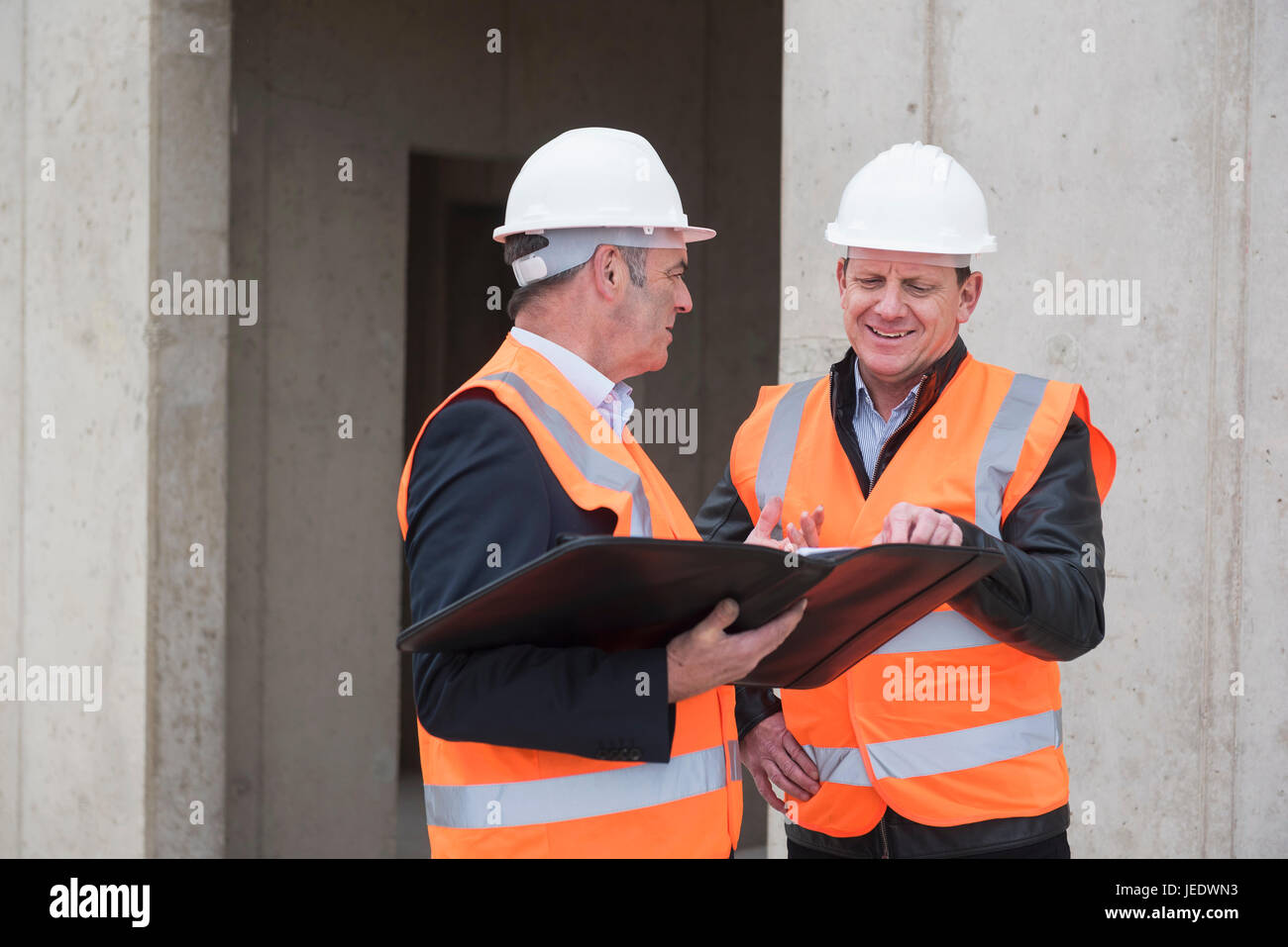 Two men wearing safety vests talking on construction site Stock Photo ...