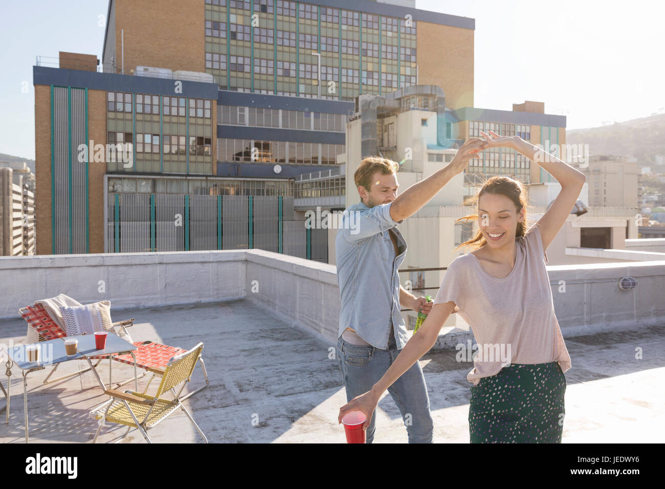 Young couple celebrating on a rooftop terrace, dancing together Stock ...