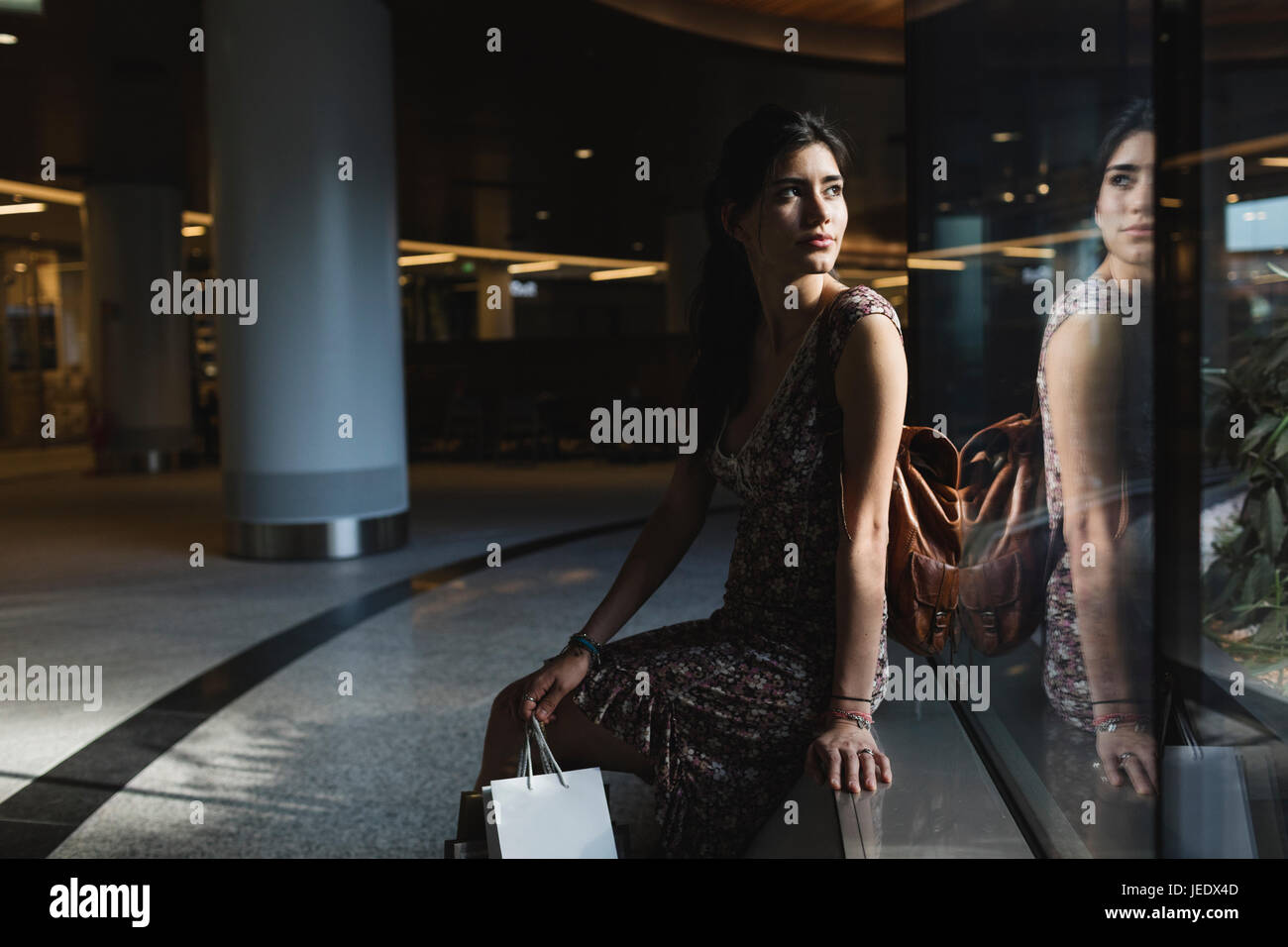 Woman sitting looking at a shop window Stock Photo - Alamy