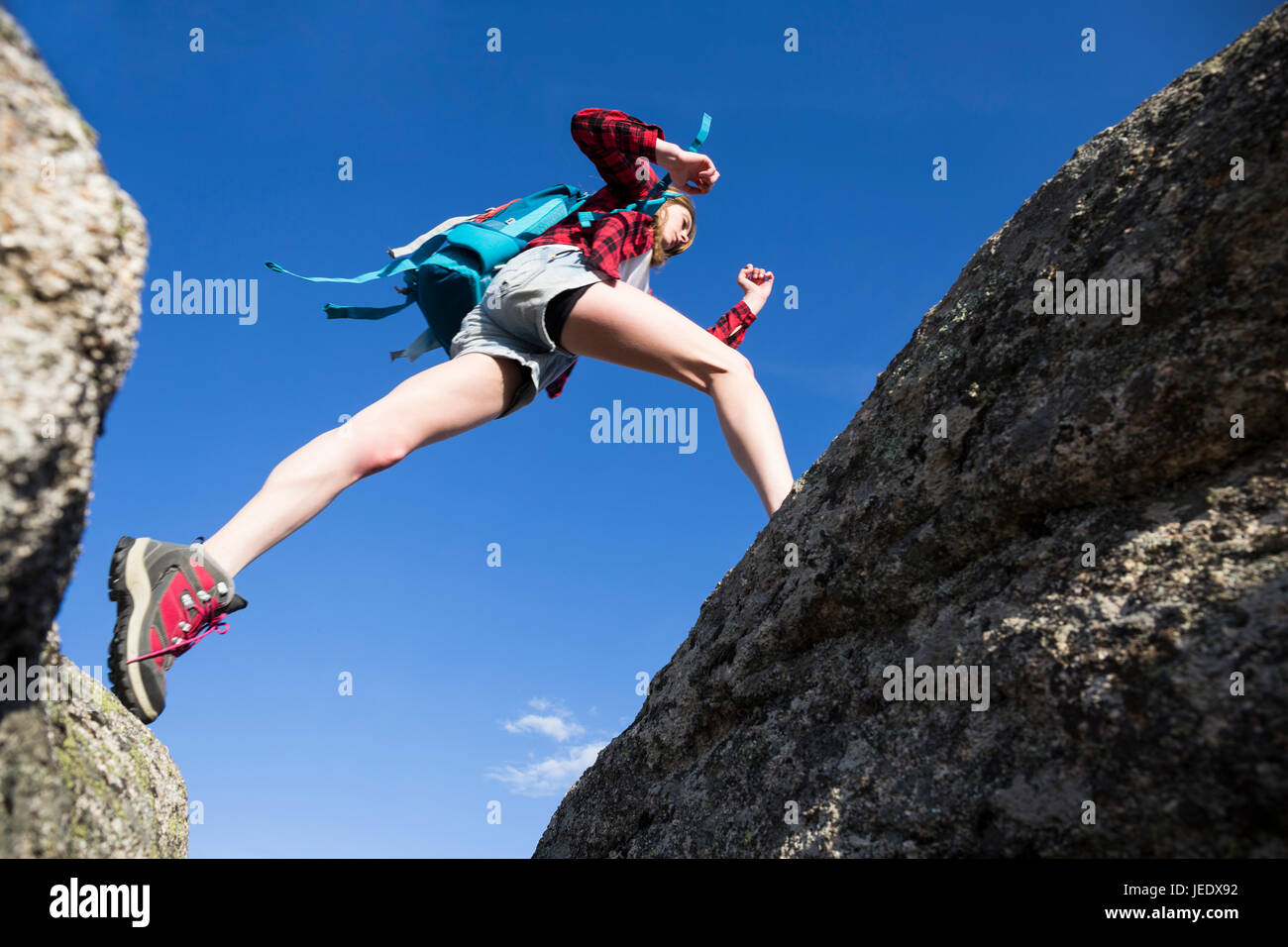 Spain, Madrid, young woman jumping between rocks during a trekking day ...